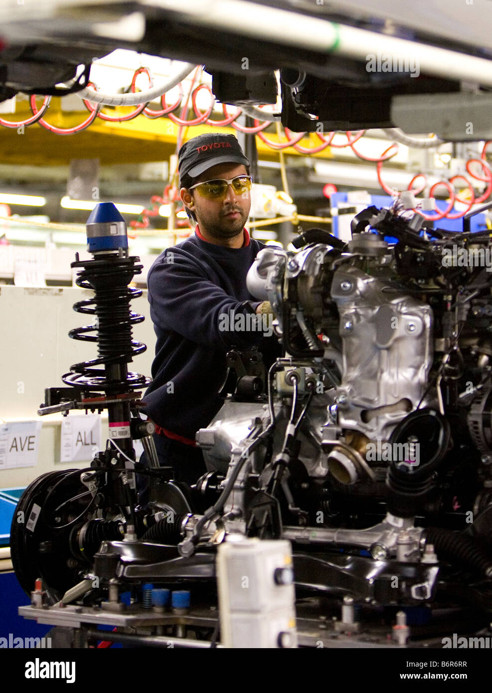 A worker at Toyota Final Assembly production line fits a part to a ...