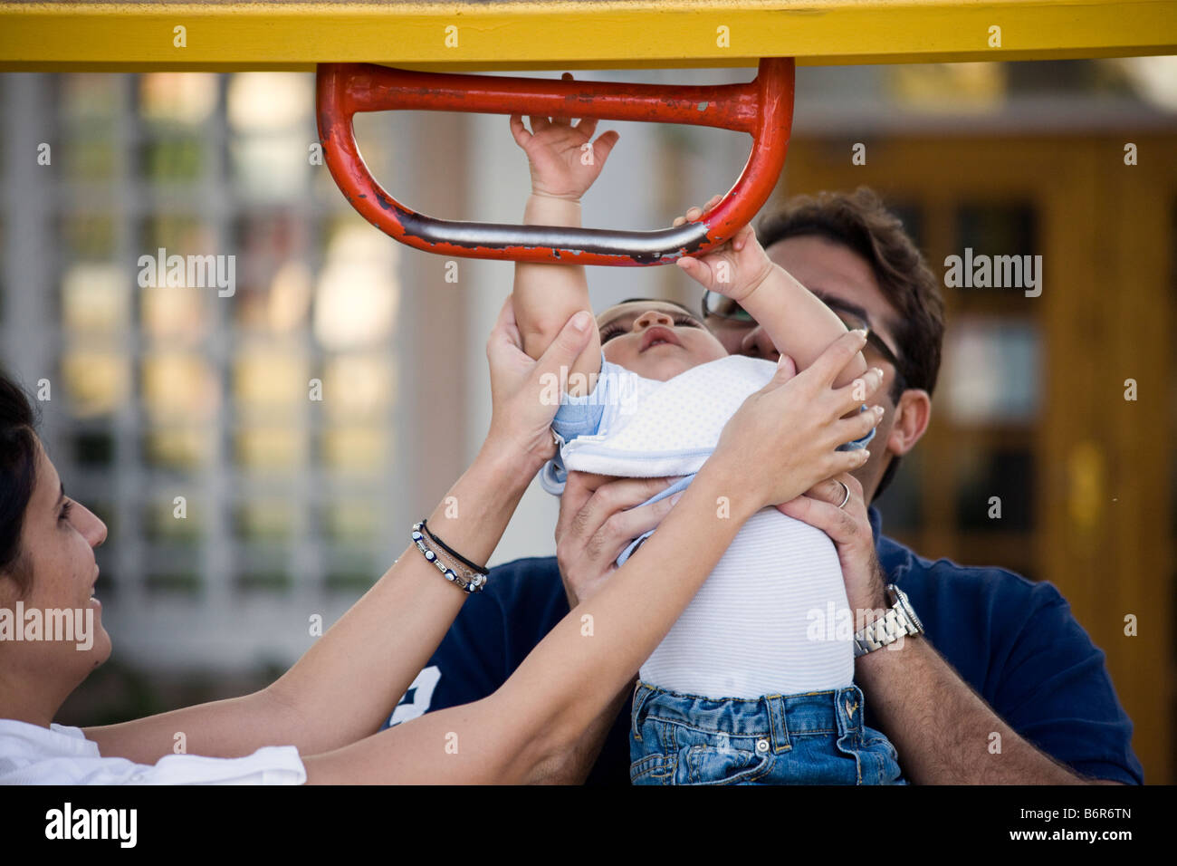 parents helping baby to reach and grasp Stock Photo - Alamy
