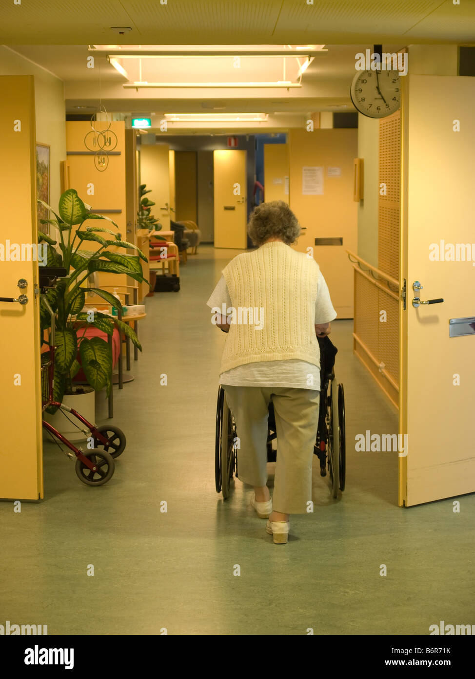old woman pushing a wheelchair in corridor of a home for old people ...