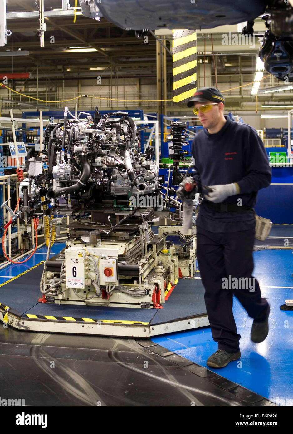 A worker at Toyota Final Assembly production line walks past the engine ...