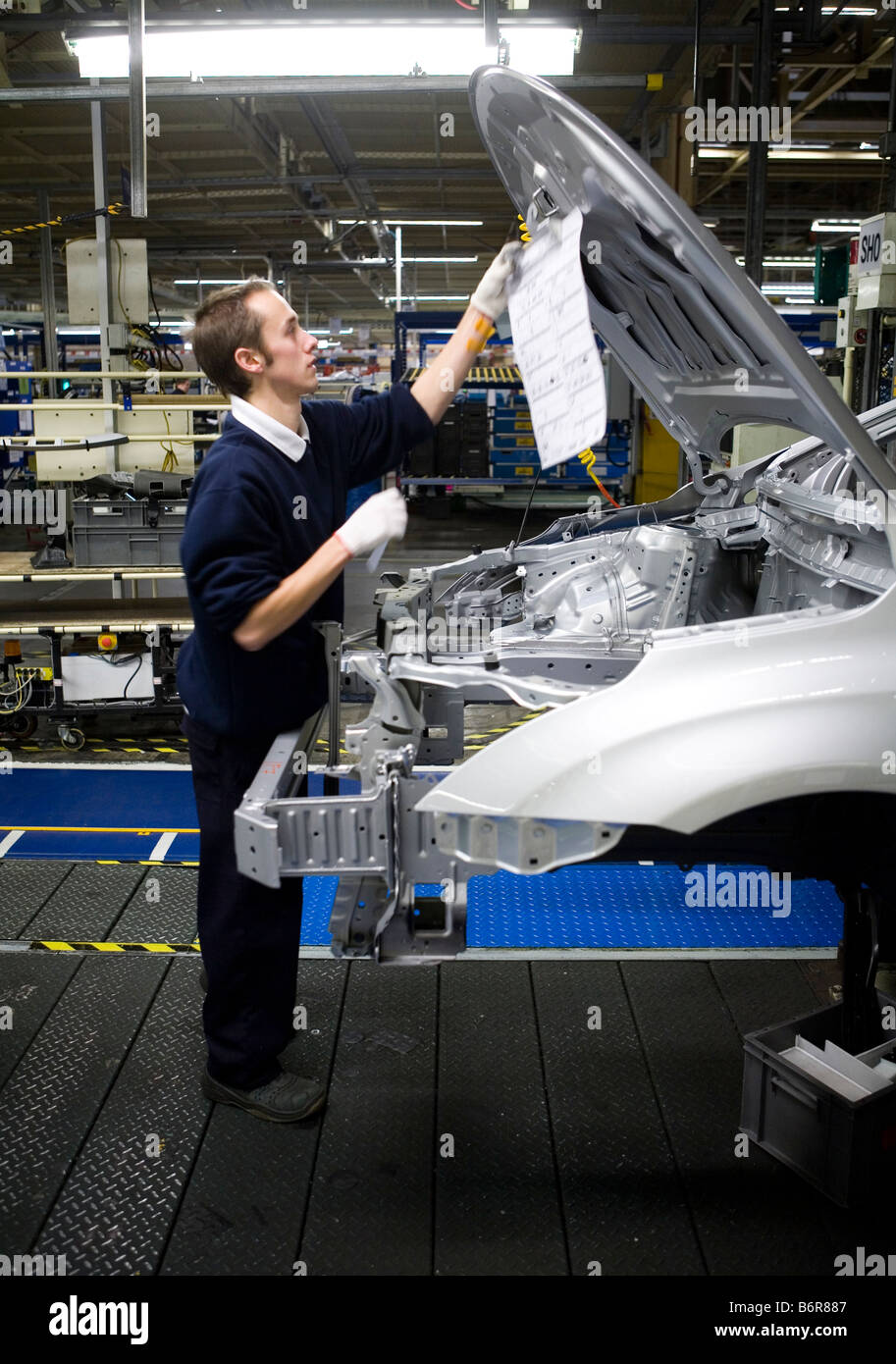 A worker at Toyota Final Assembly production line fits a part to the ...