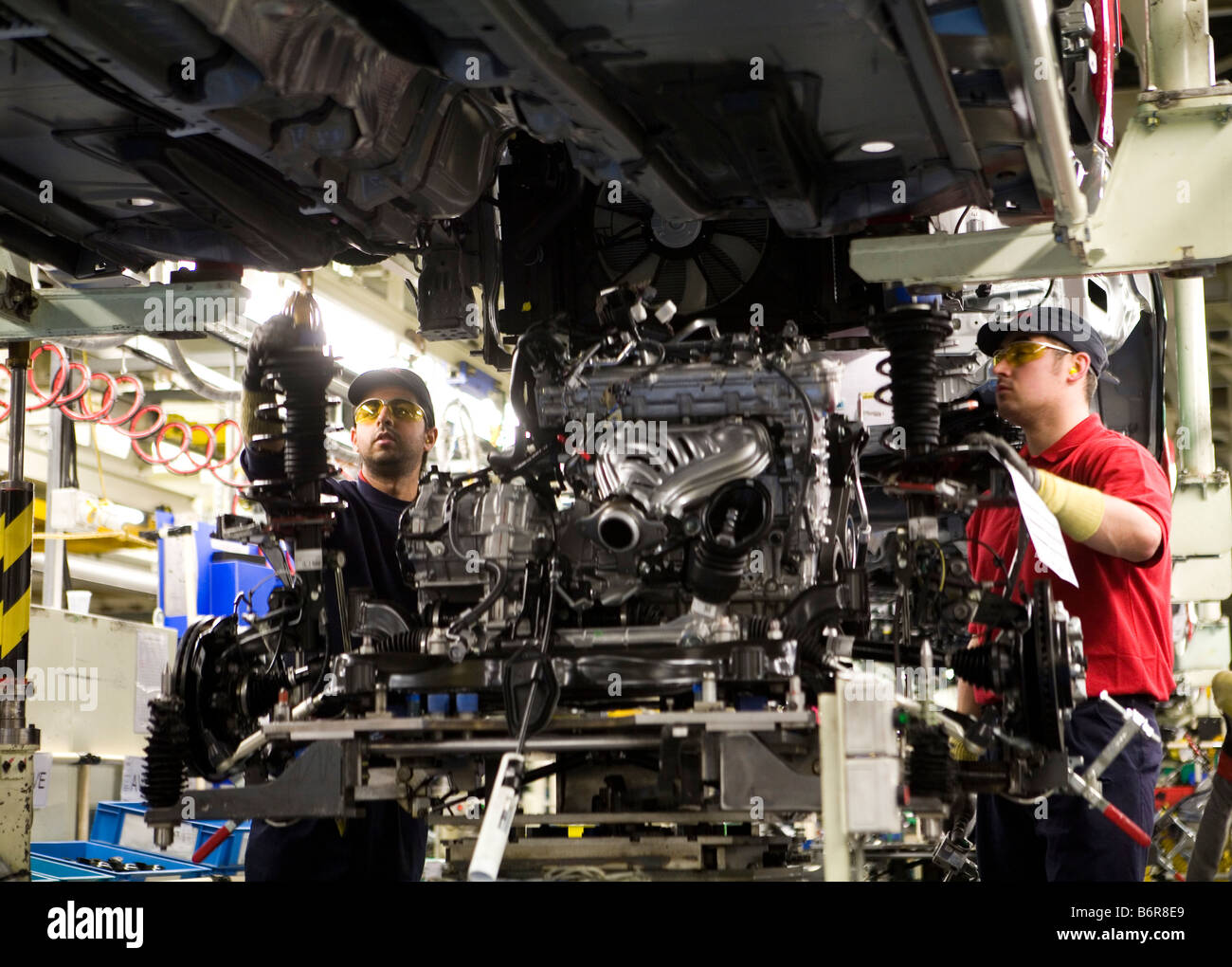 Workers at Toyota Final Assembly production line prepare the engine for ...