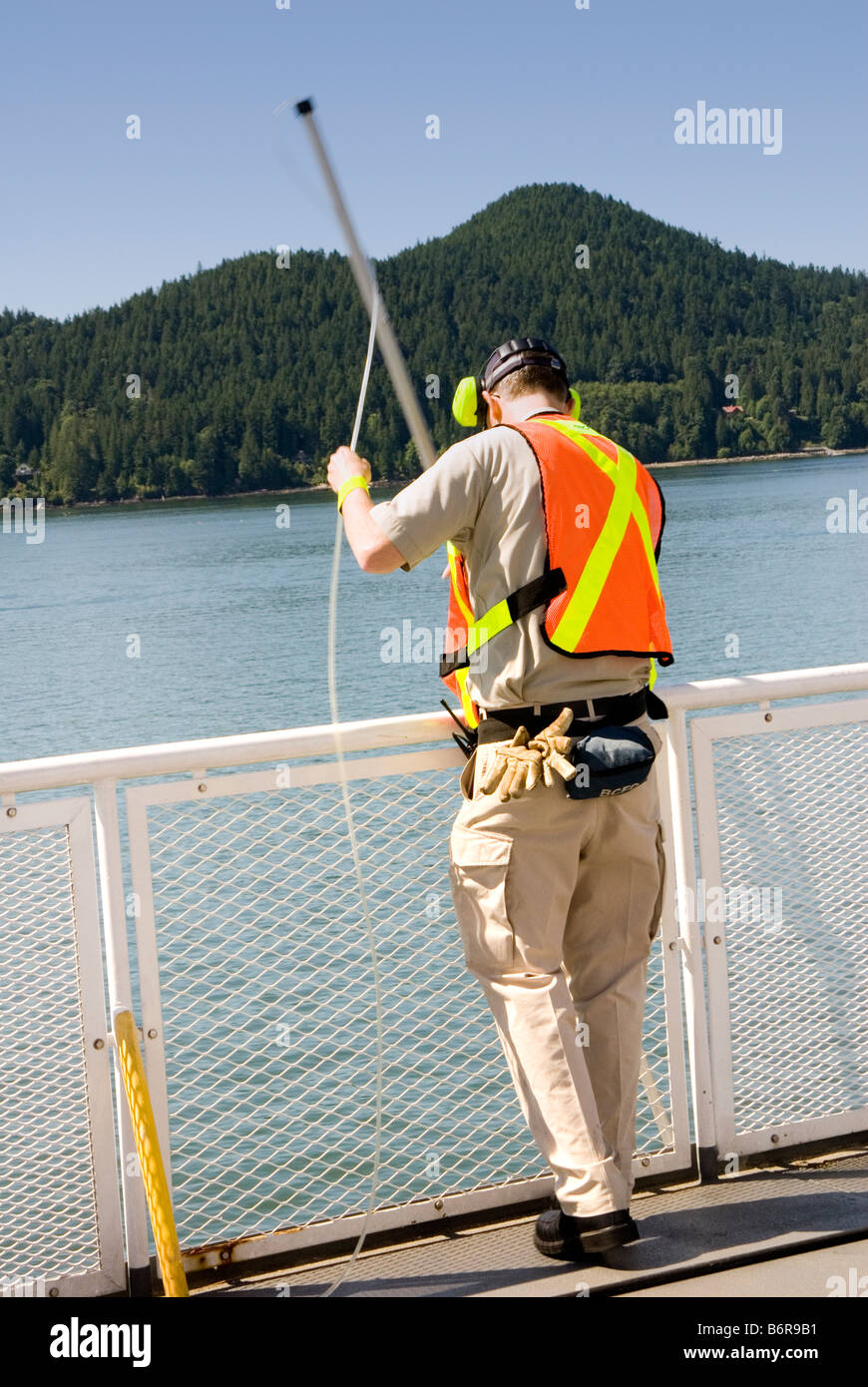 Ferry worker with safety vest on deck of boat Stock Photo - Alamy