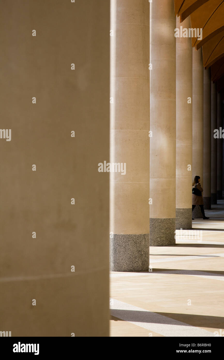 A pedestrian walks among the columns in Paternoster Square, London ...
