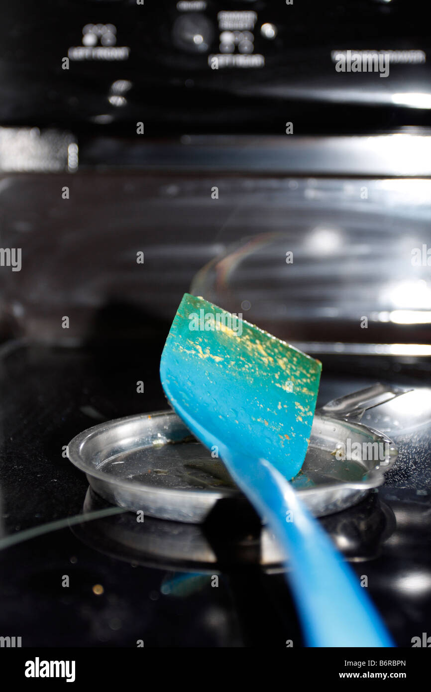 Steaming blue plastic spatula with yellow sauce on metal coaster Stock ...