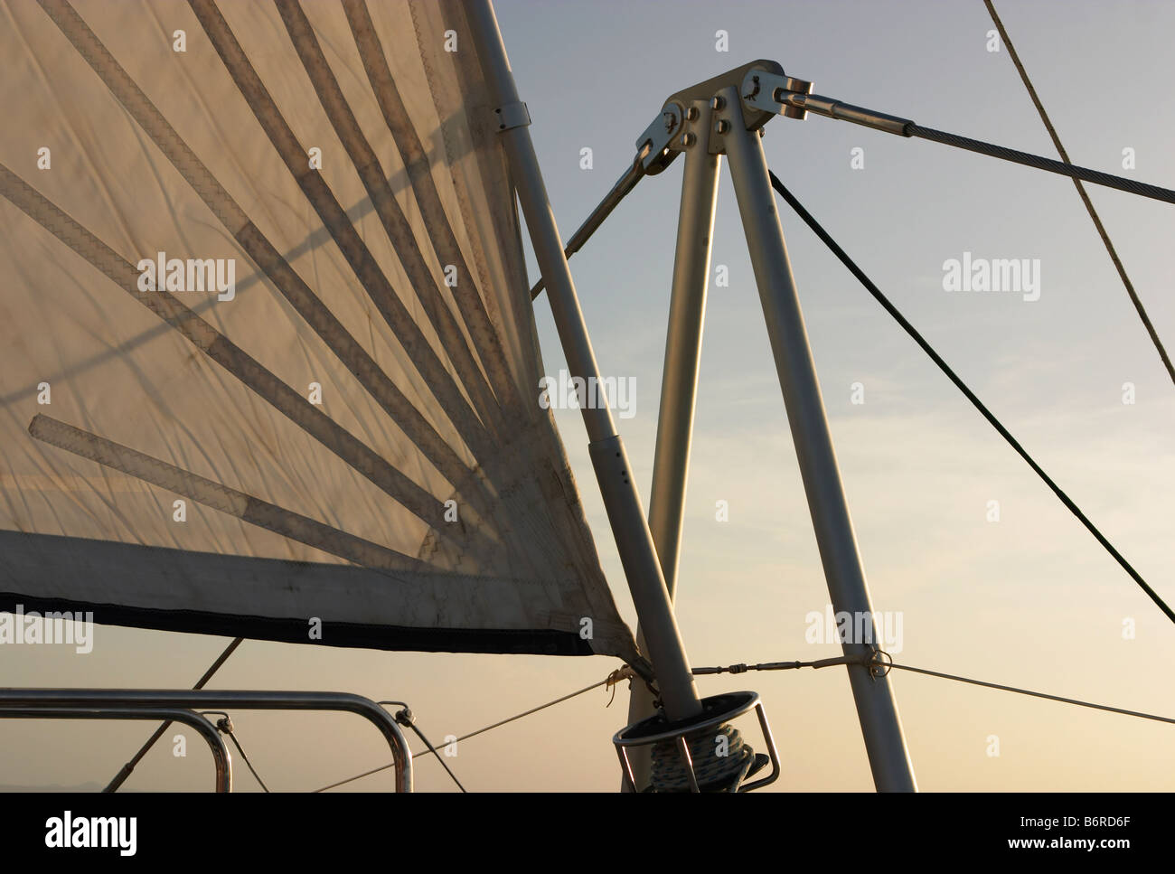 cream white sail with rigging plus guardrail and a blue sky background ...