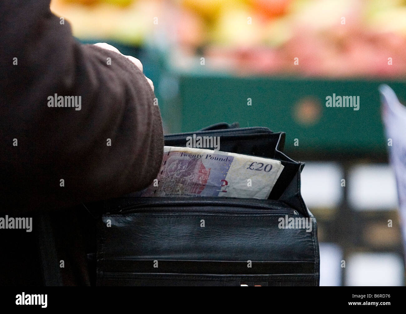 A customer with wallet showing money and 20 notes at a market stall ...