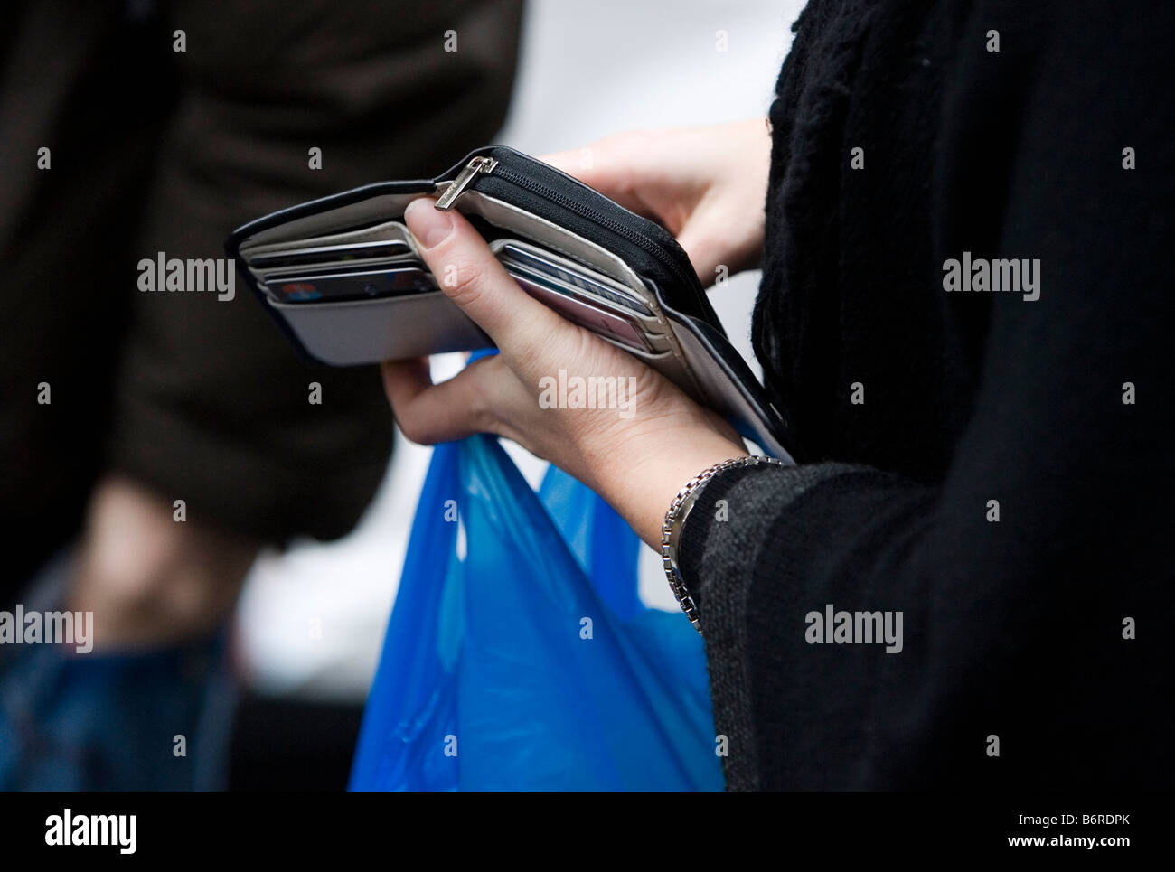 A customer with wallet showing money and credit cards at a market stall ...