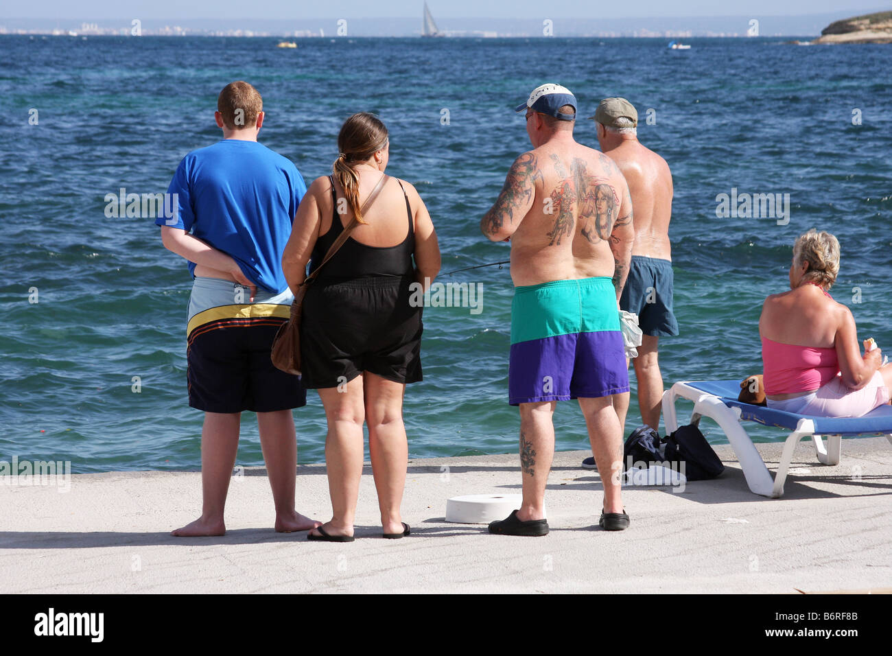 Back view of group of people looking at the sea and fishermen in ...
