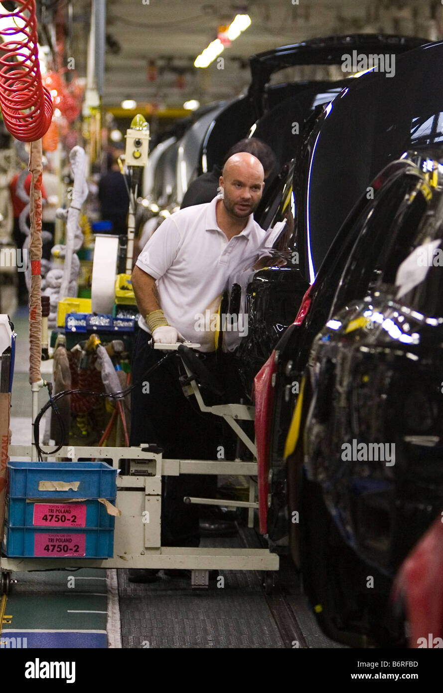A worker at Toyota Final Assembly production line fits a part to a ...