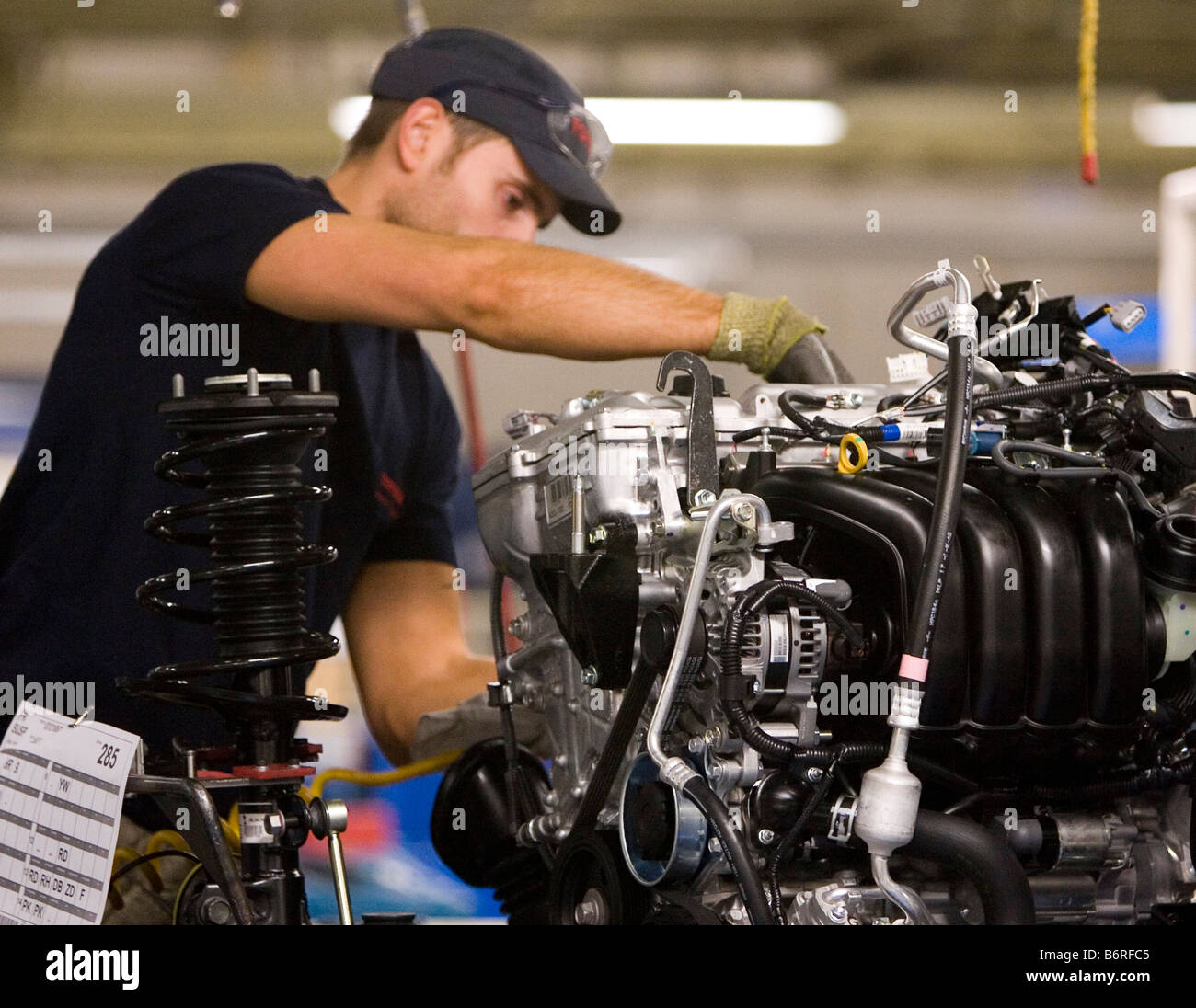 A worker at Toyota Final Assembly production line fits a part to a ...