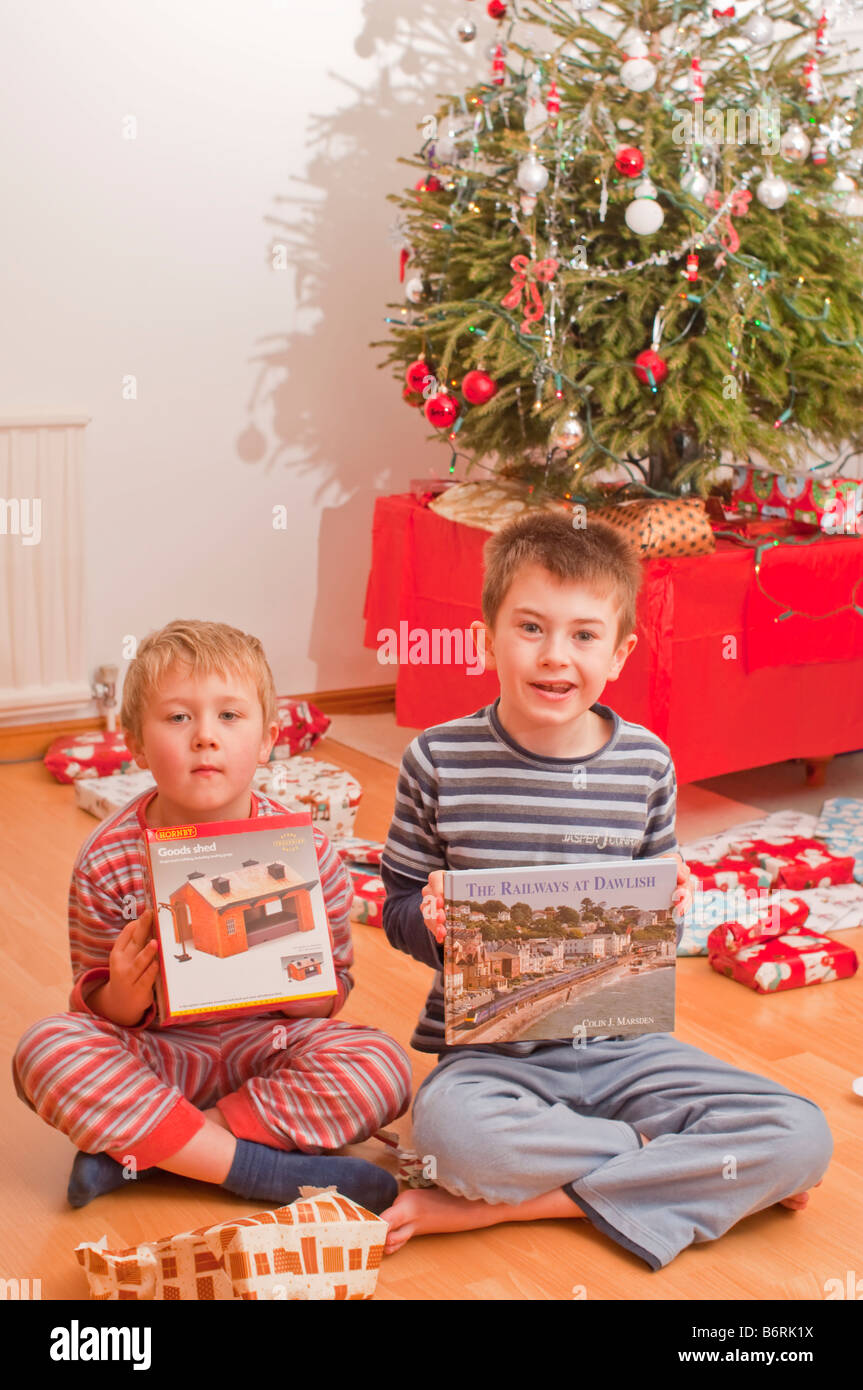 Two children opening their christmas presents under the tree on ...