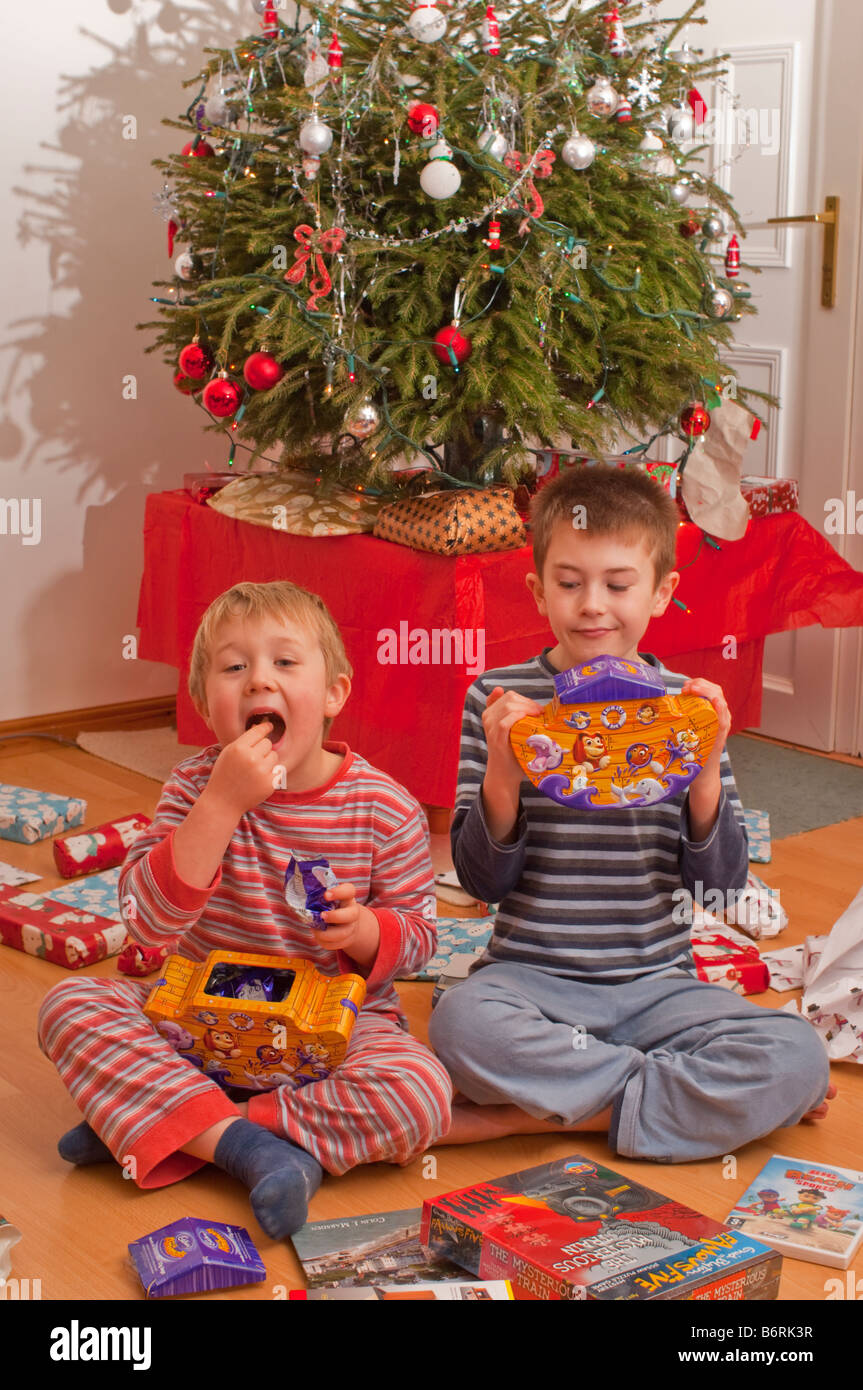 Two children opening their christmas presents under the tree on ...