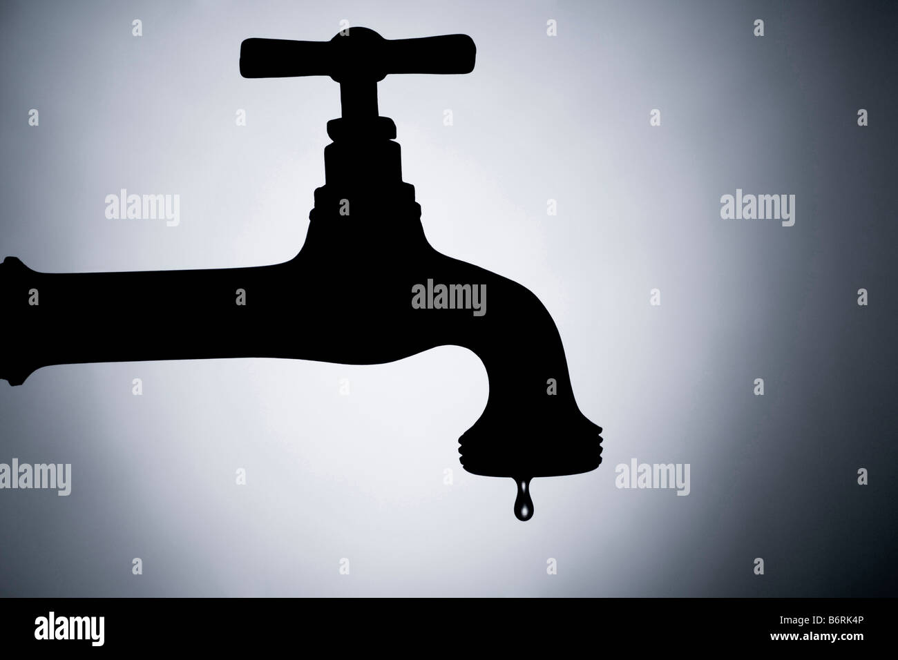 a silhouette of a leaking tap against bluish background Stock Photo - Alamy