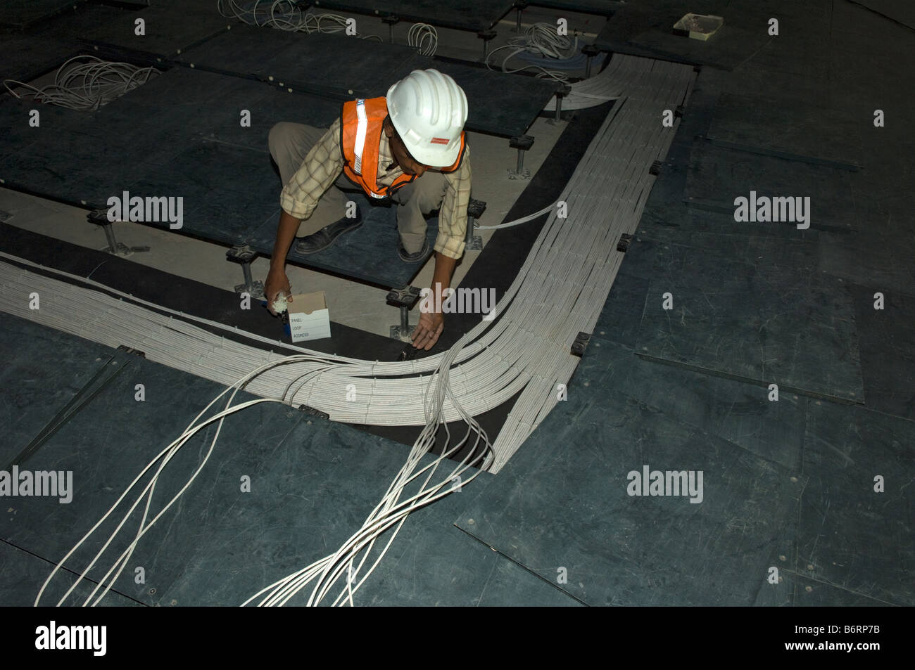 Engineer inspecting a structured cabling installation under a raised ...