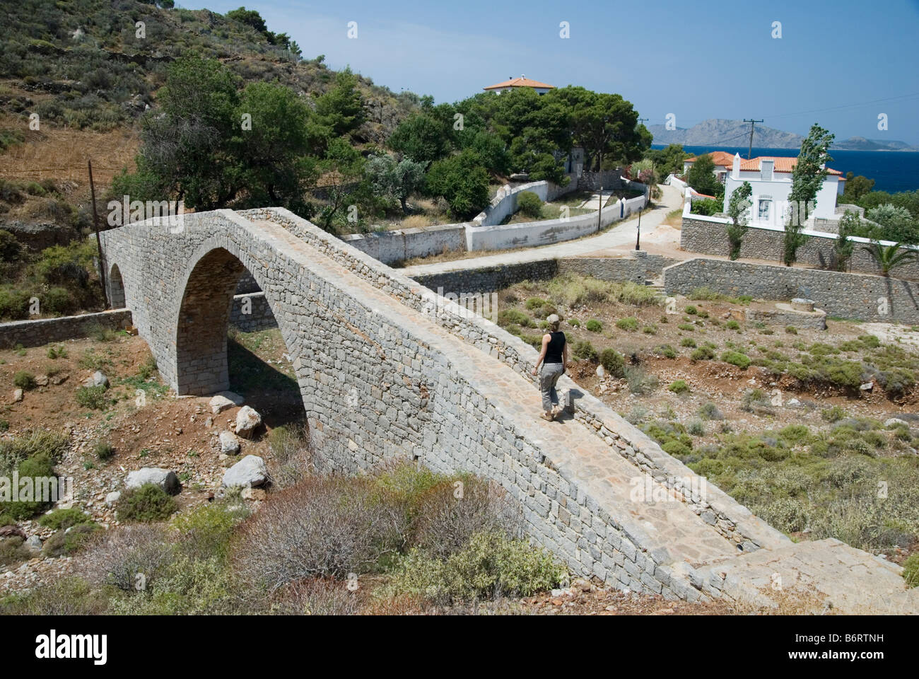 A tourist walks over a restored 19th century stone bridge in the pretty ...