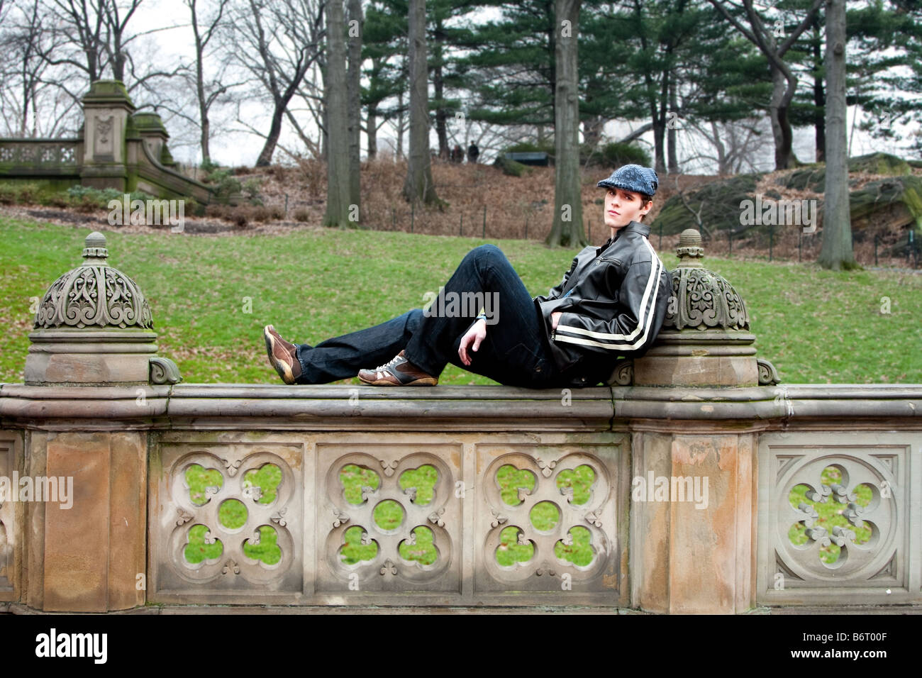 Handsome caucasian guy sitting on railing with landscape background ...