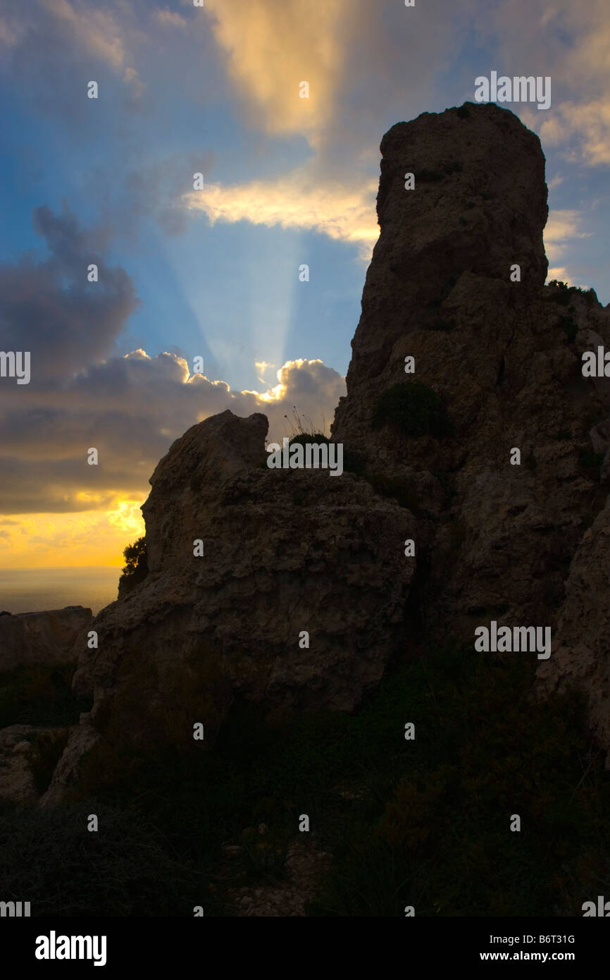 Sun setting behind rock formation Stock Photo - Alamy