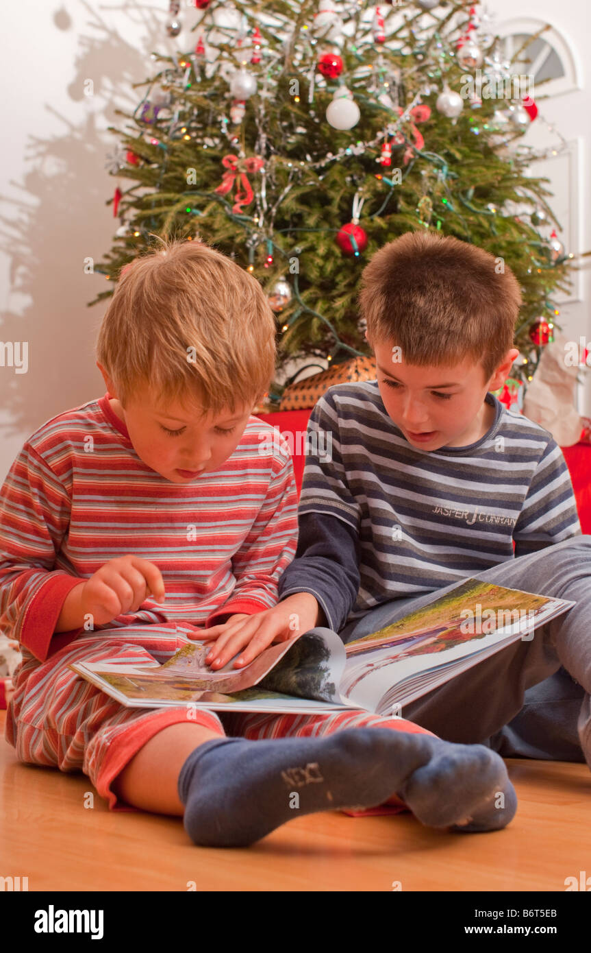 Two children opening their christmas presents under the tree on ...