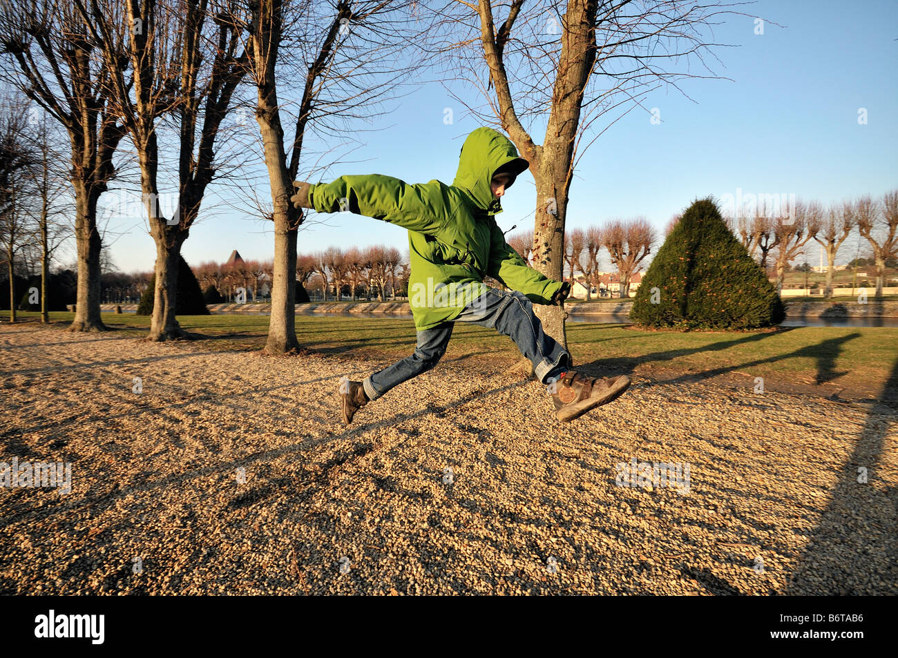 Boy making big jump in park alley with willows Stock Photo - Alamy