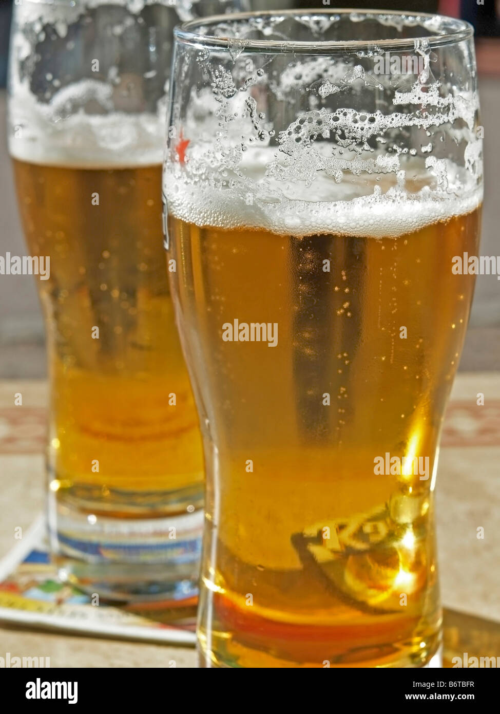 two half full glasses of beer on table Stock Photo - Alamy