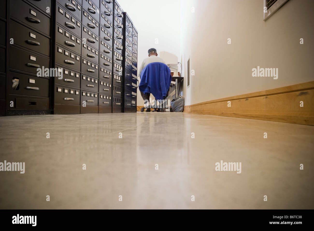 Man in an office building working at a desk next to file cabinets Stock ...
