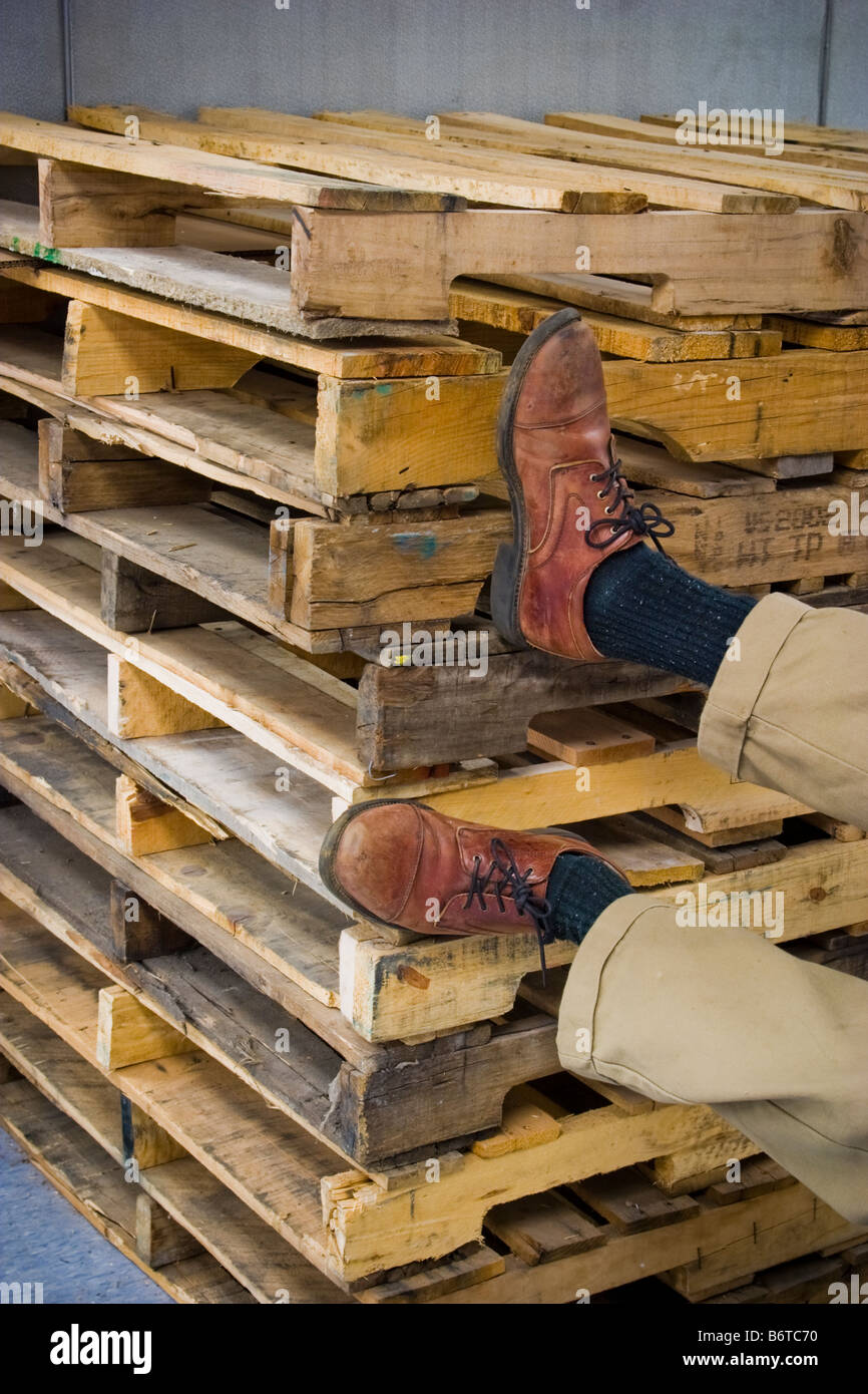Man s feet resting on a pile of wooden pallets MODEL and LOCATION ...