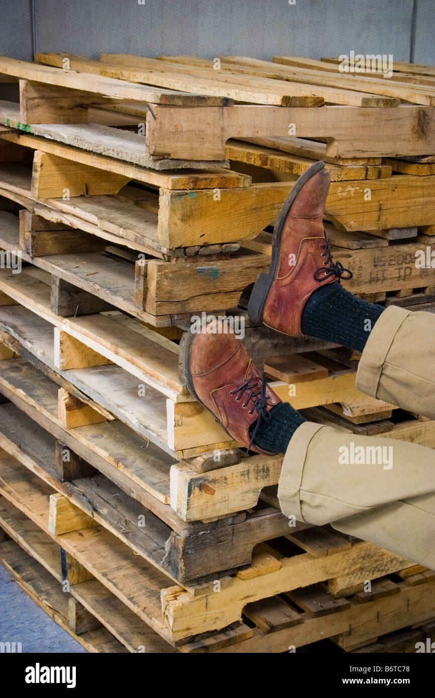 Man s feet resting on a pile of wooden pallets MODEL and LOCATION ...