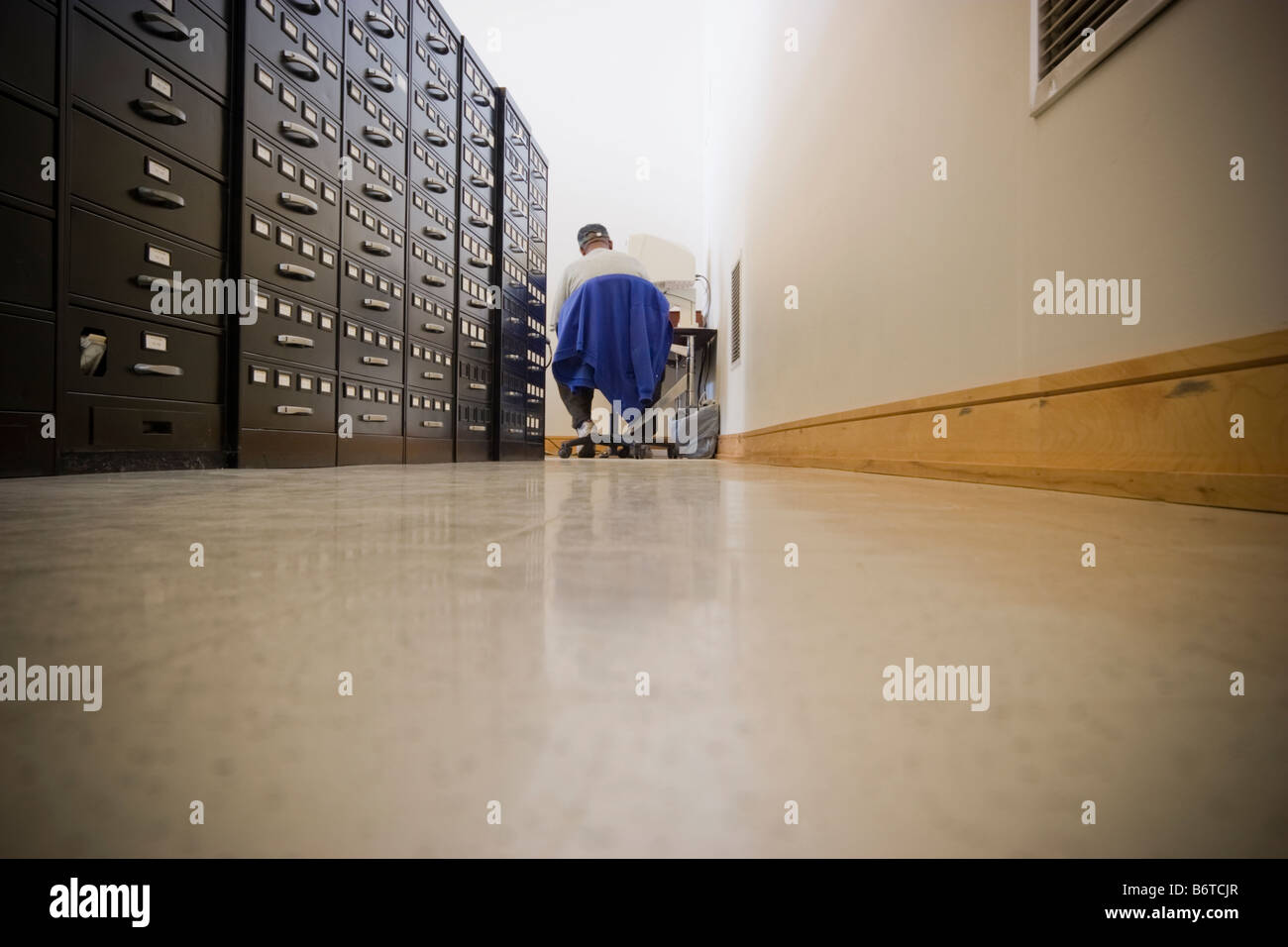 Man in an office building working at a desk next to file cabinets Stock ...