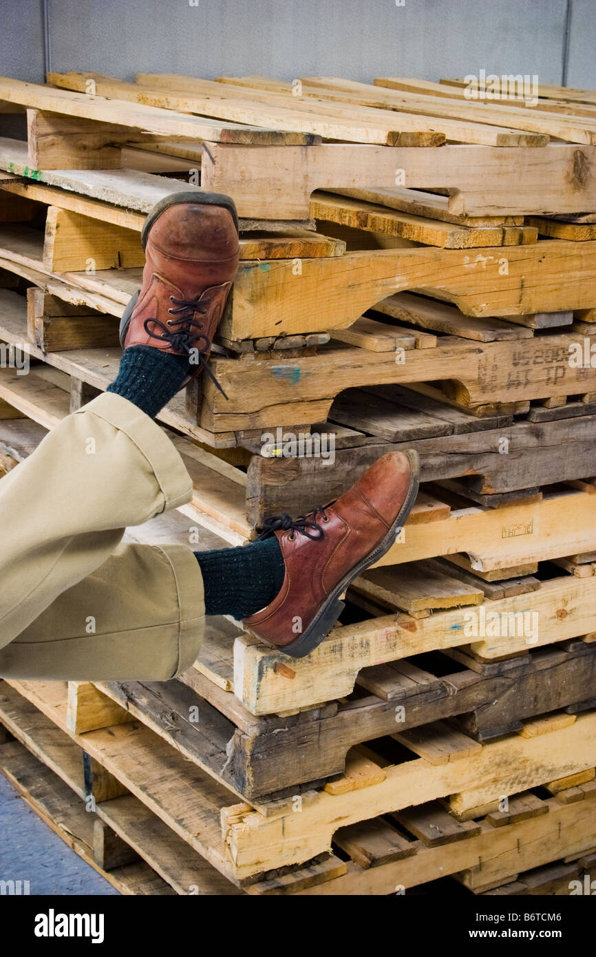 Man s feet resting on a pile of wooden pallets MODEL and LOCATION ...