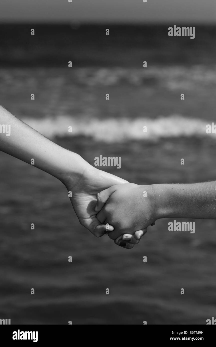 Holding hands at beach in front of waves Stock Photo - Alamy
