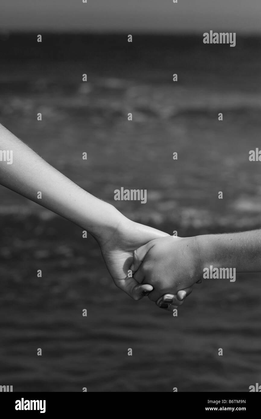 Holding hands at beach in front of waves Stock Photo - Alamy