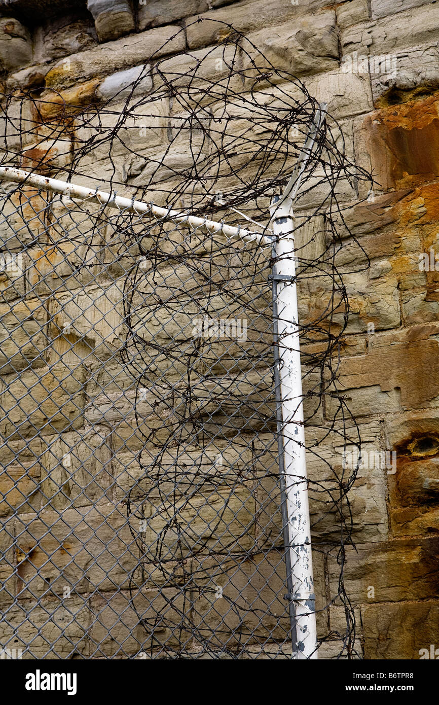 Image of a prison security gate and a brick wall covered with coils of ...
