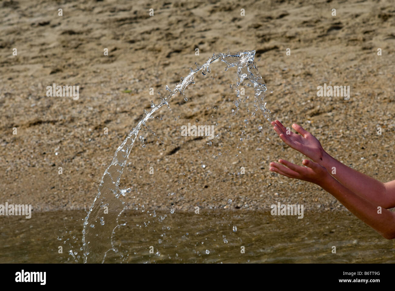 Water flying from childs hands at beach Stock Photo - Alamy