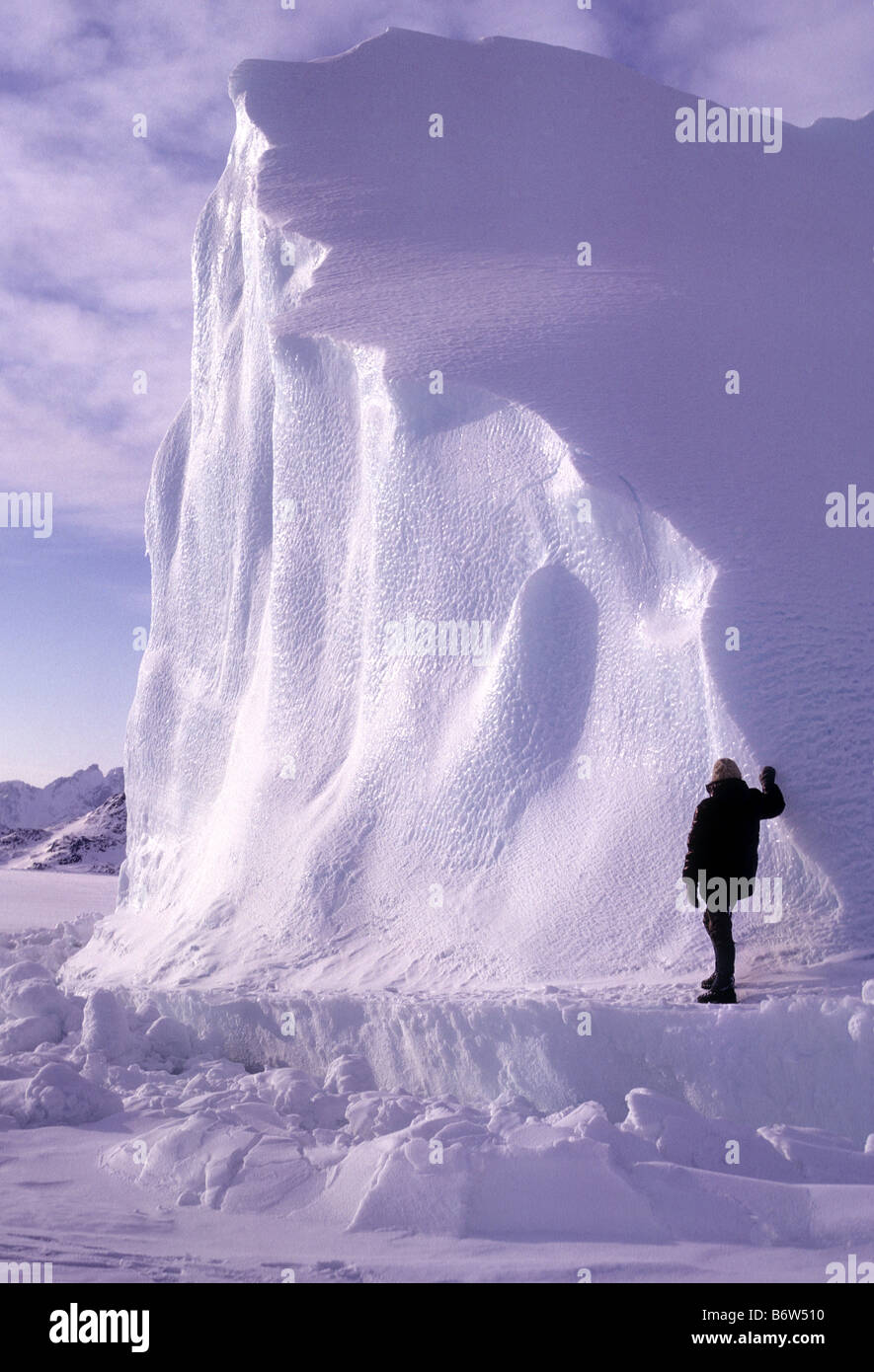 Climber on large iceberg in sea ice near Kulusuk East Greenland The ...