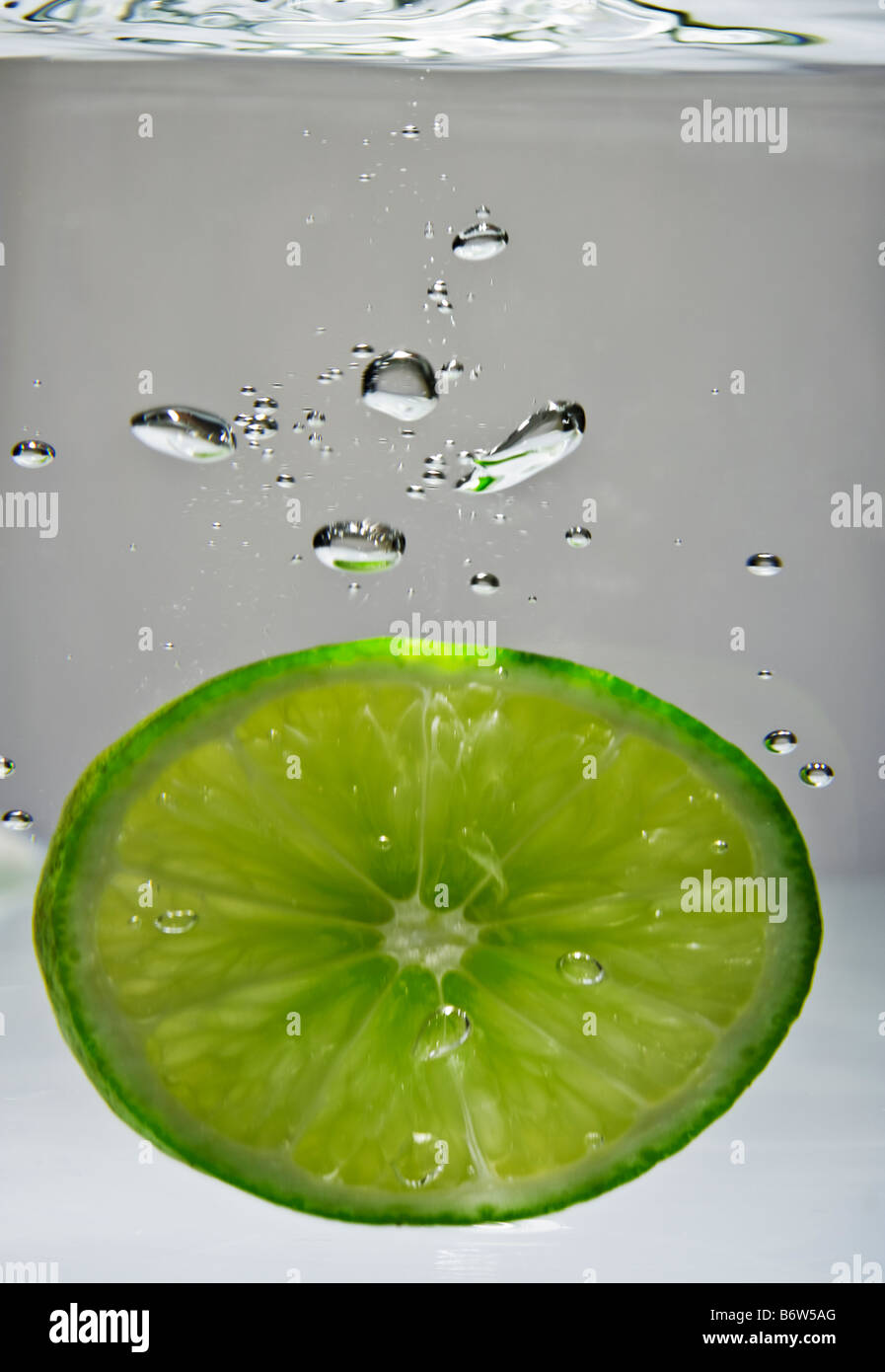 slice of lime splashing into water Stock Photo - Alamy