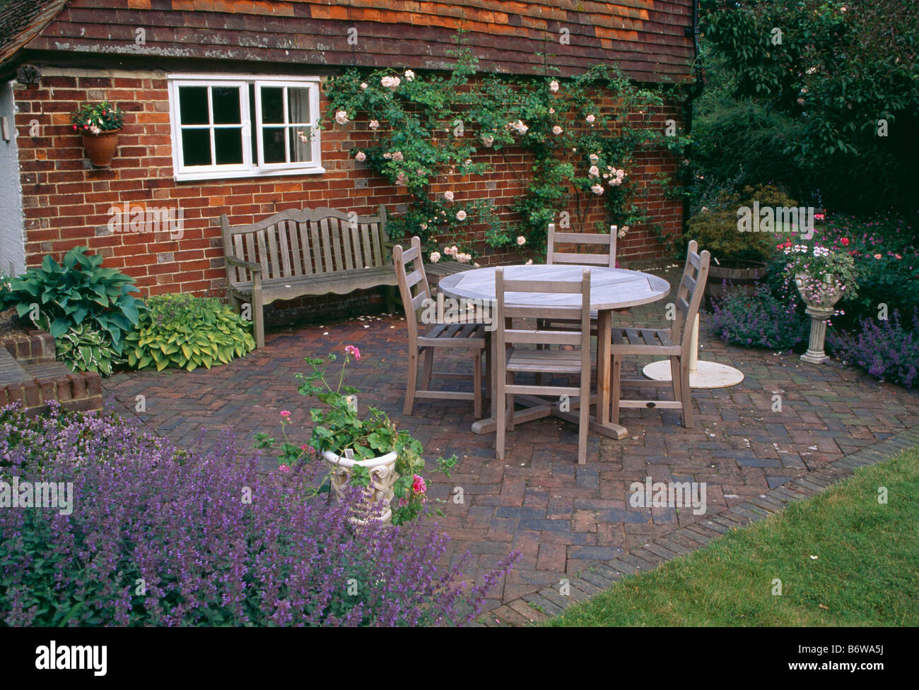 Wooden table and chairs on herringbone brick paved patio in front of ...