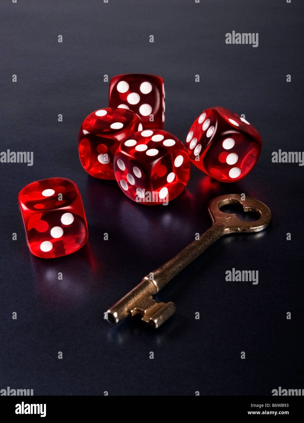 Five clear red game dice and a skeleton key, a conceptual still life ...