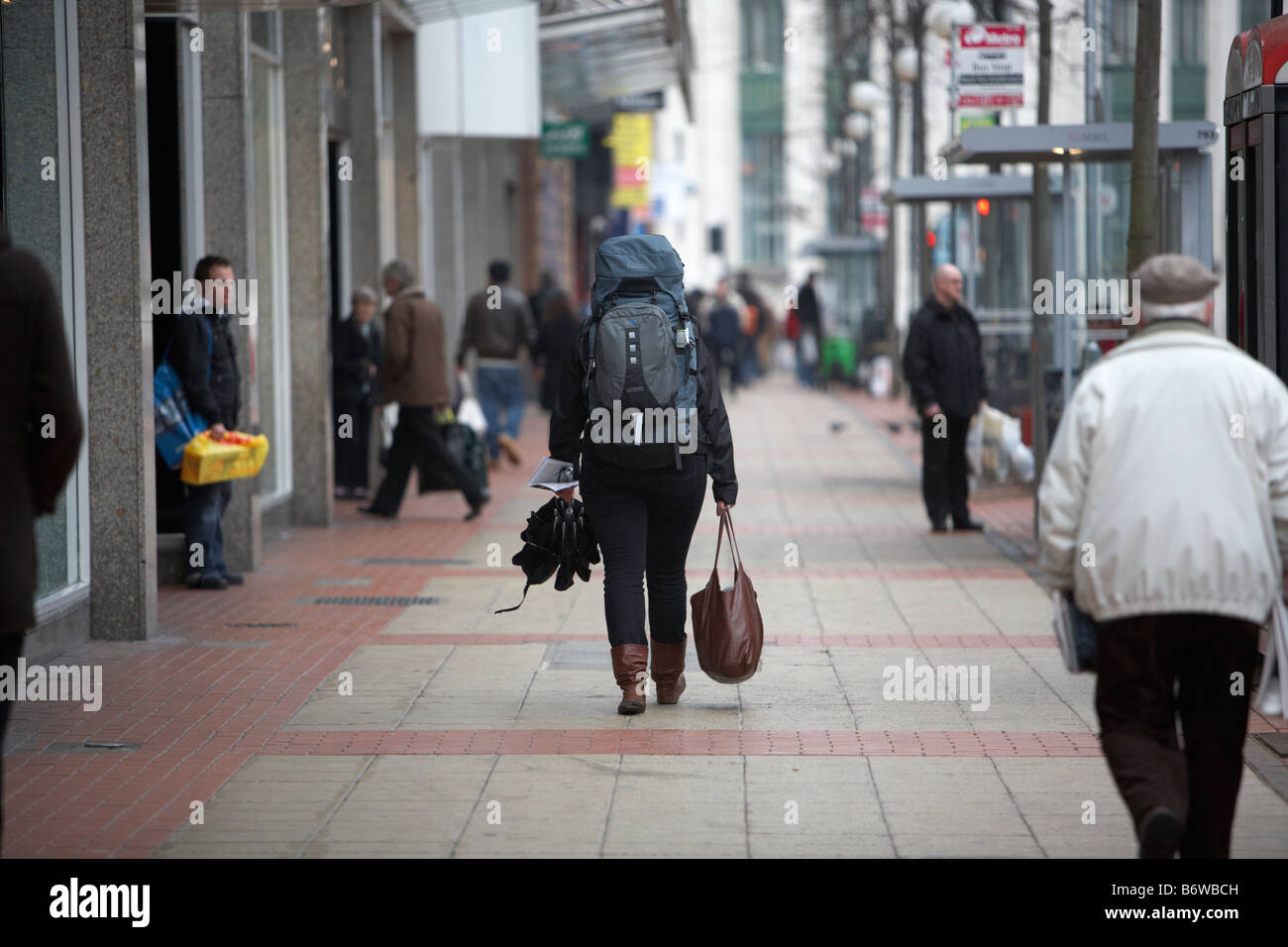 lone female backpack traveller walking along city street carrying heavy ...
