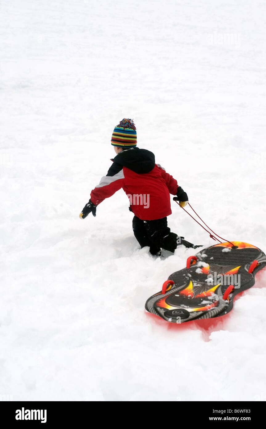 Young Boy pulling his sled through snow Stock Photo - Alamy