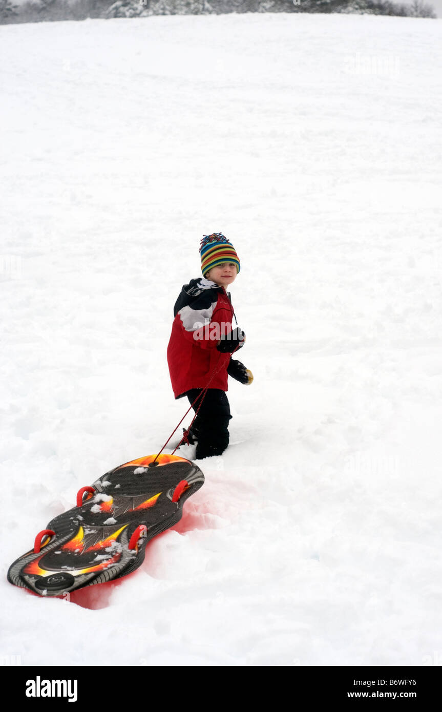 Young Boy pulling his sled through snow Stock Photo - Alamy