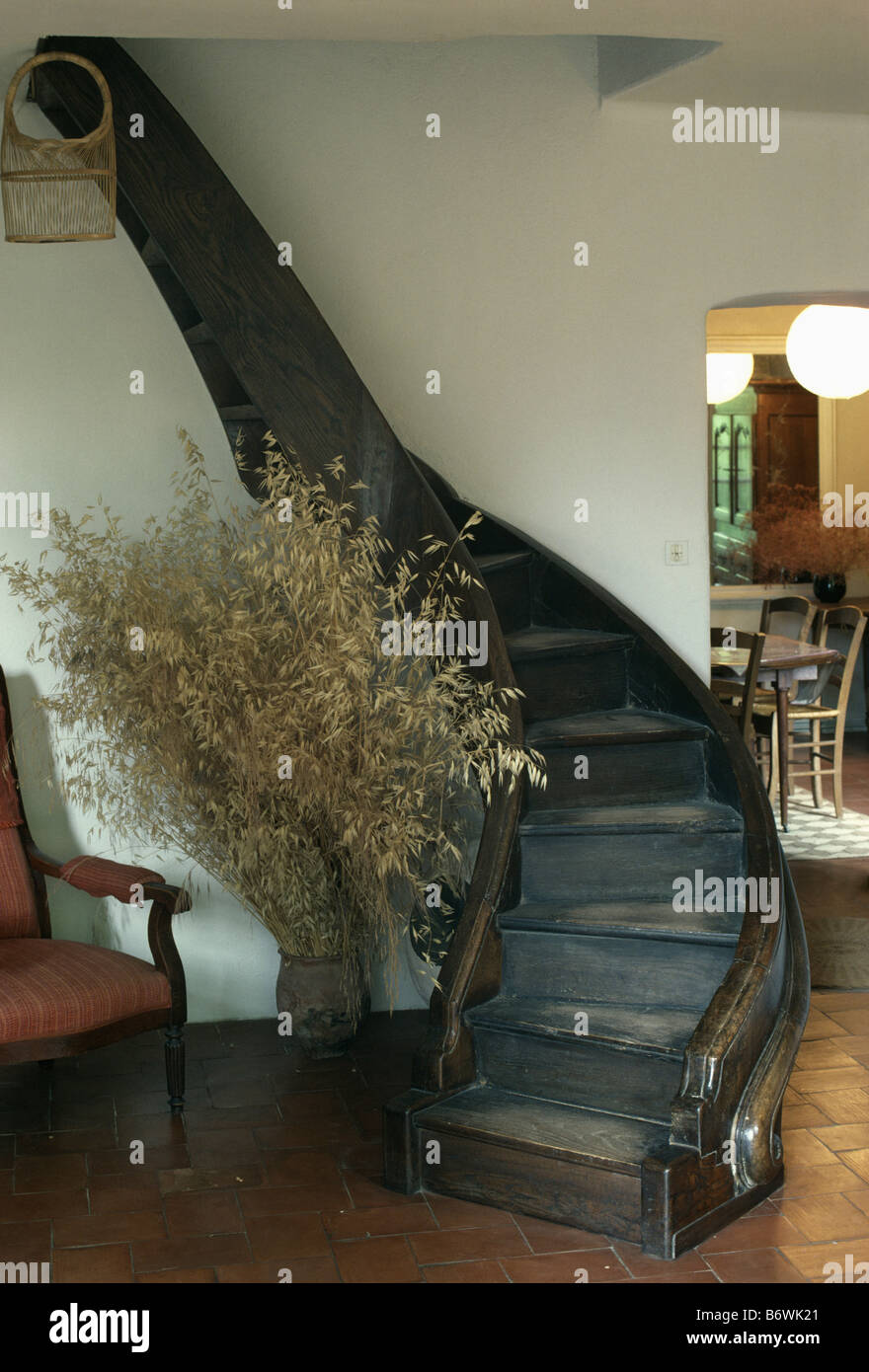 Dried wheat in vase at the bottom of dark wooden carved staircase in ...