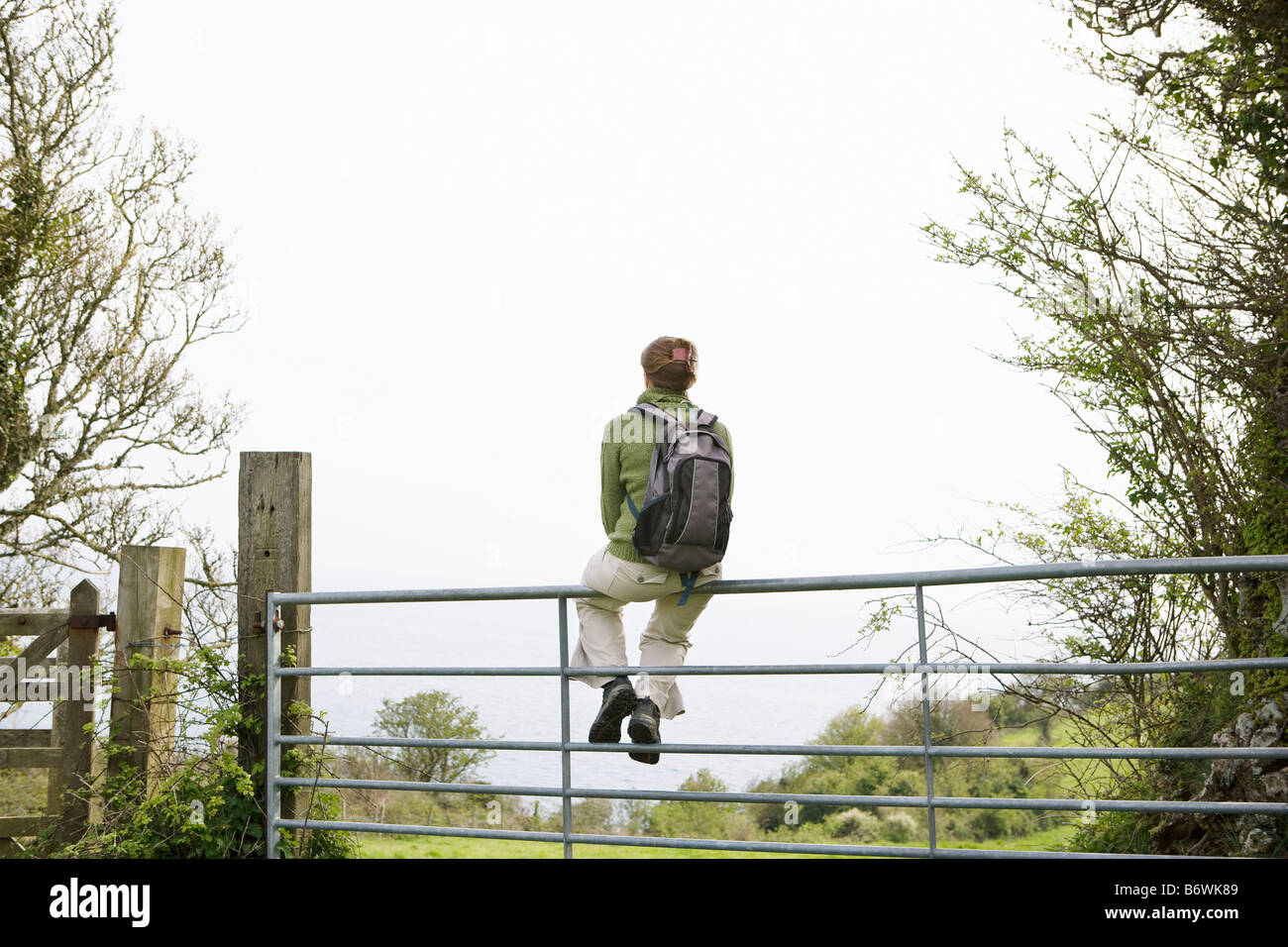 Young Woman Sitting on a Gate Stock Photo - Alamy