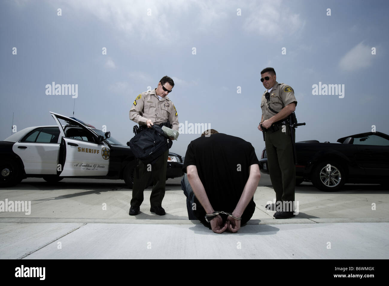 Two police officers discovering drugs in backpack of arrested man Stock ...