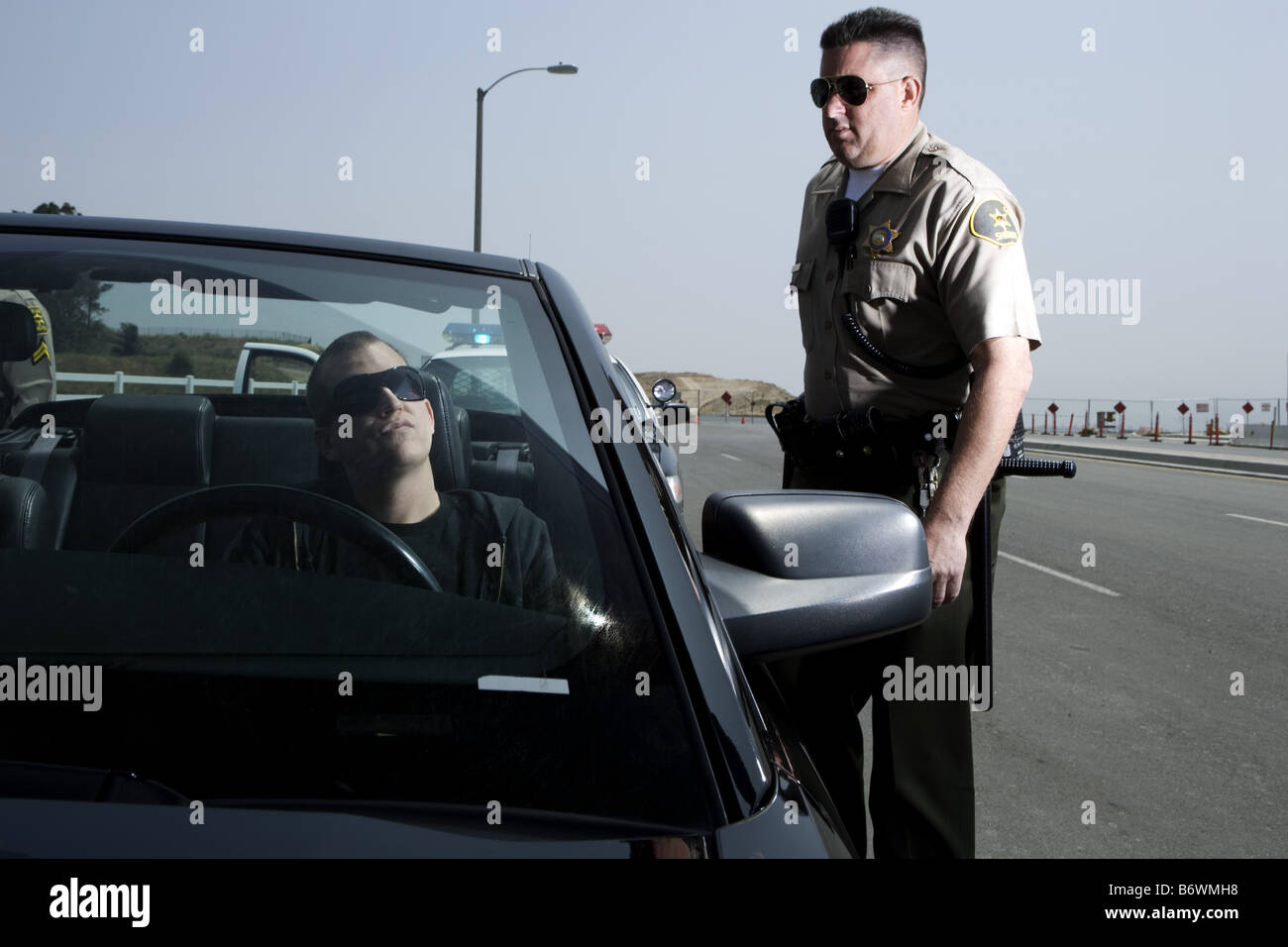 Two police officers apprehend man in black Mustang Stock Photo - Alamy