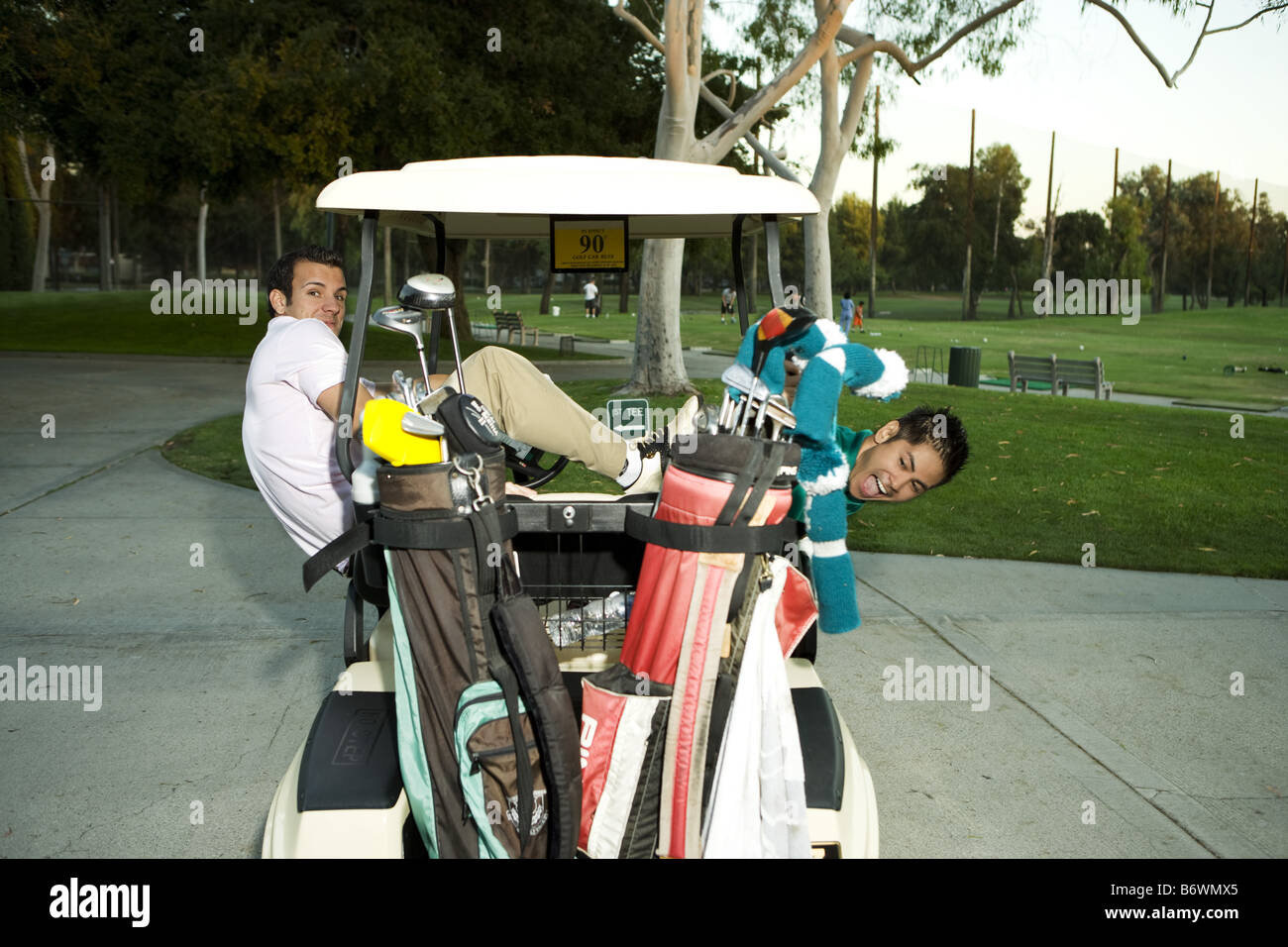Two men having fun on golf cart Stock Photo - Alamy