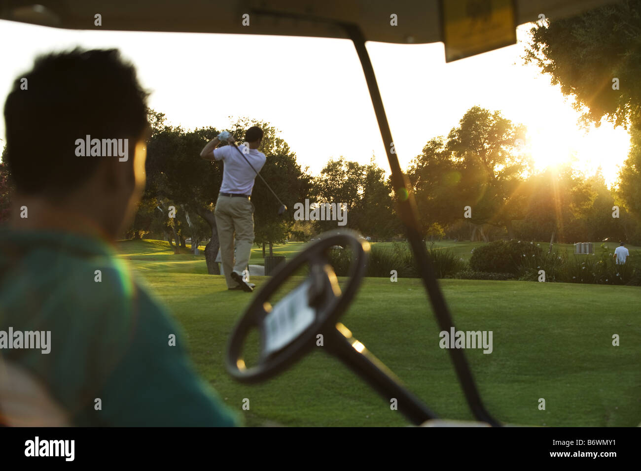 Golfer watching friend play golf Stock Photo - Alamy