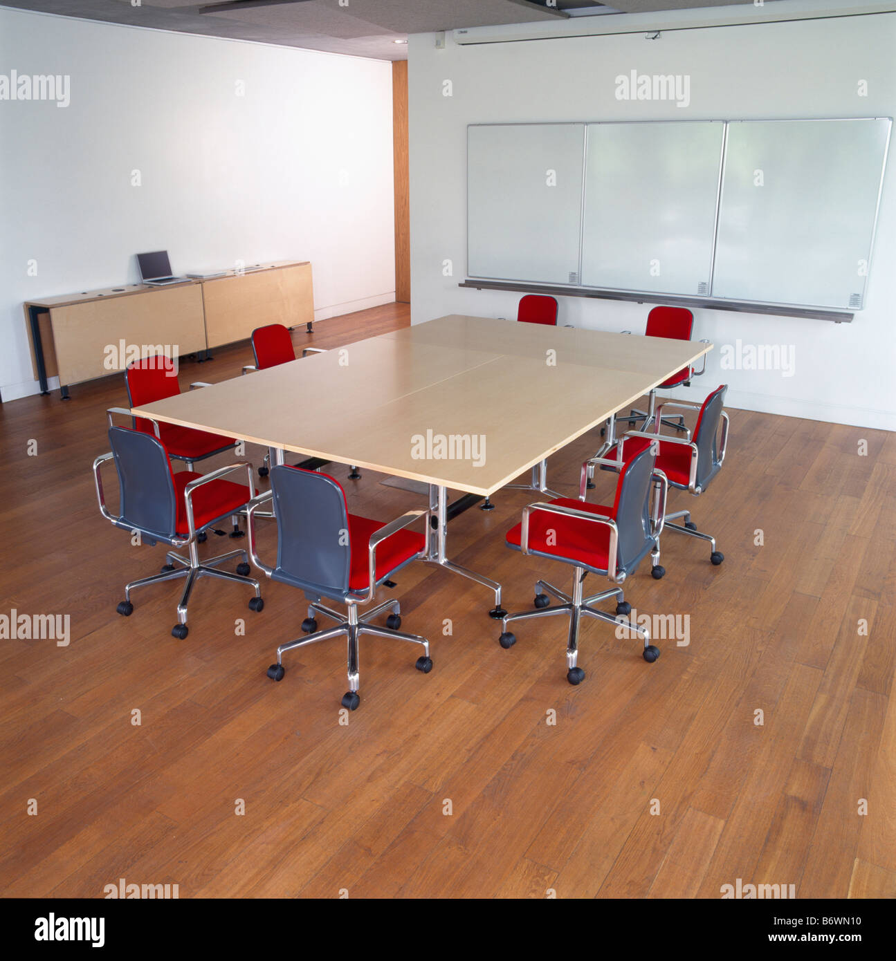 Blue and red swivel chairs and pale wood boardroom table in modern ...
