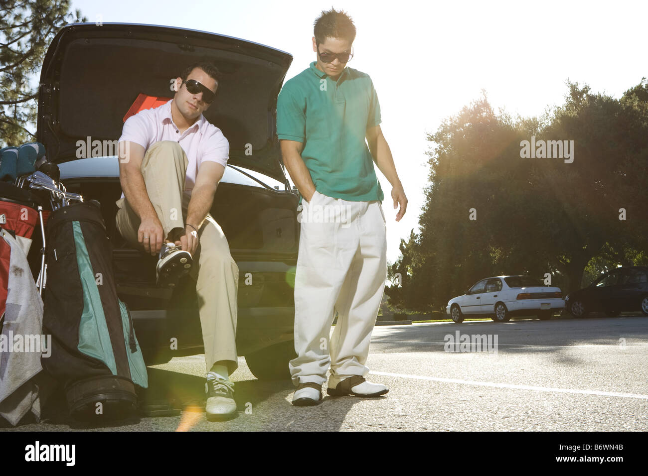 Two golfers putting on shoes on back of car Stock Photo - Alamy