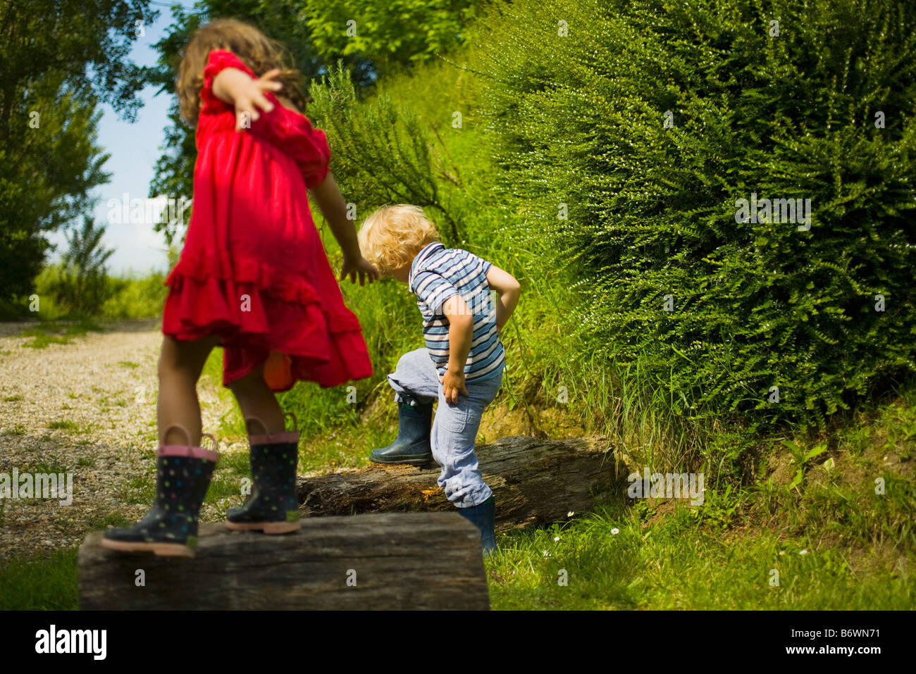 Boy and girl stepping on logs Stock Photo - Alamy
